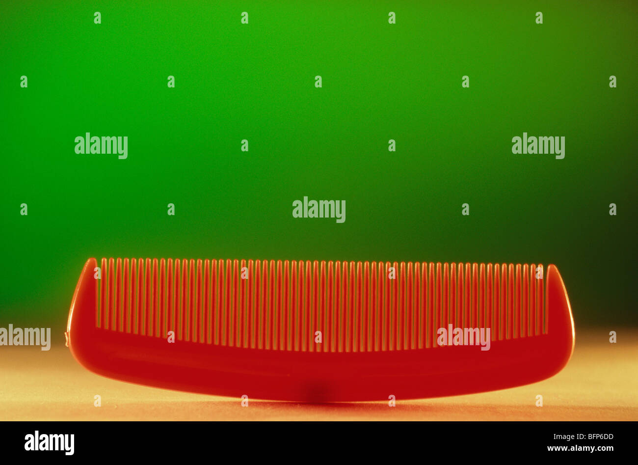 Red plastic comb against green background Stock Photo - Alamy