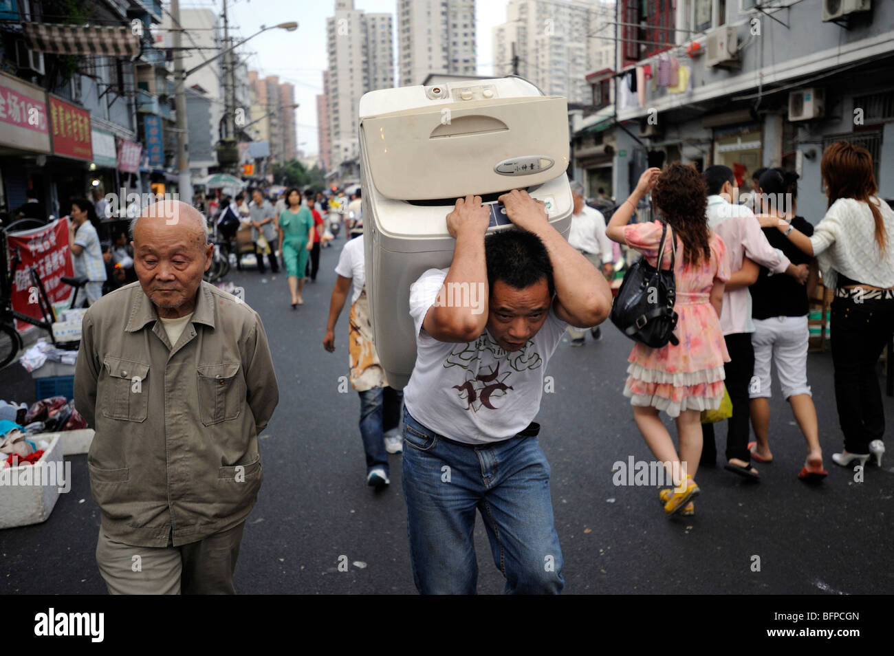 A man carries a washing machine in a street of Shanghai, China.08-Oct ...