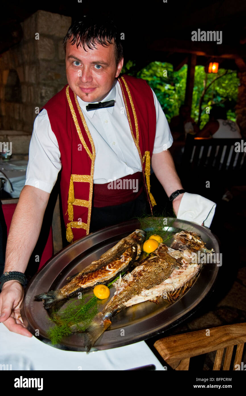 Waiter presents grilled fresh fish at restaurant Stari Mlini, Ljuta ...