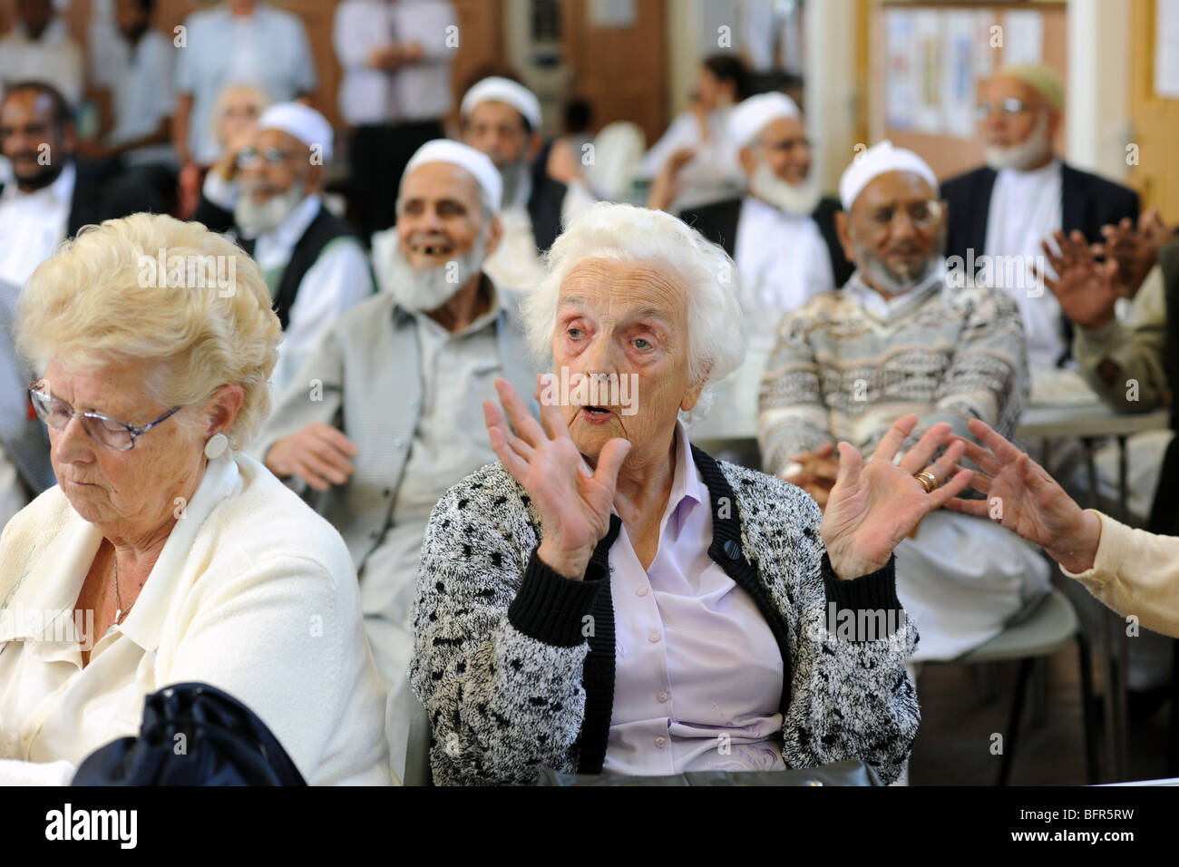 A mixed multi-cultural group of elderly people exercise in their chairs ...