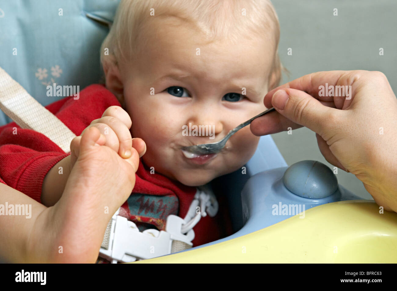 amusing baby with a spoon in a mouth Stock Photo - Alamy
