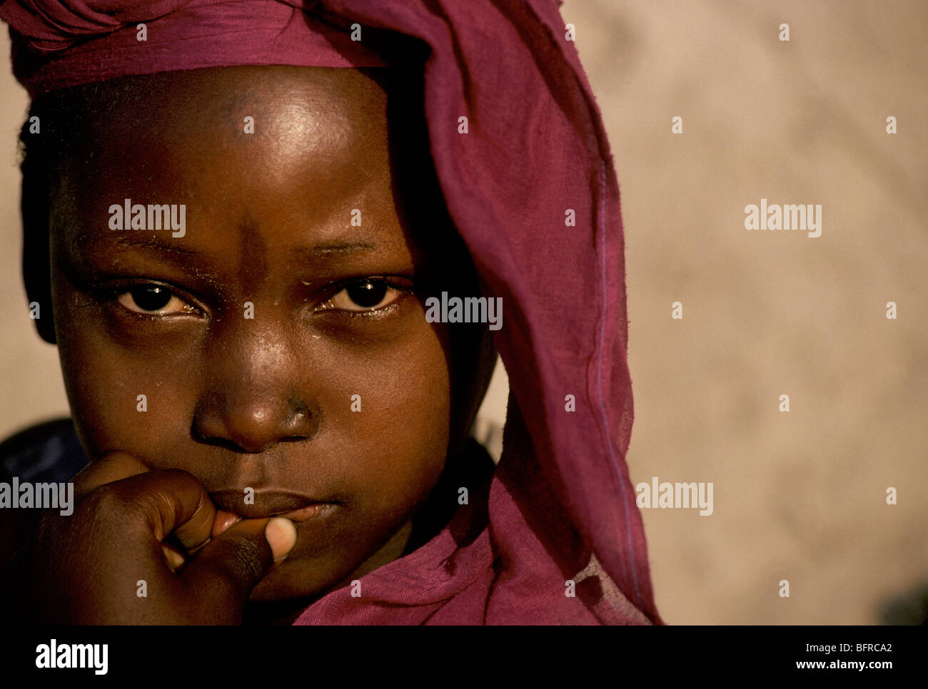 Portrait of a young African child wearing a maroon head scarf Stock ...