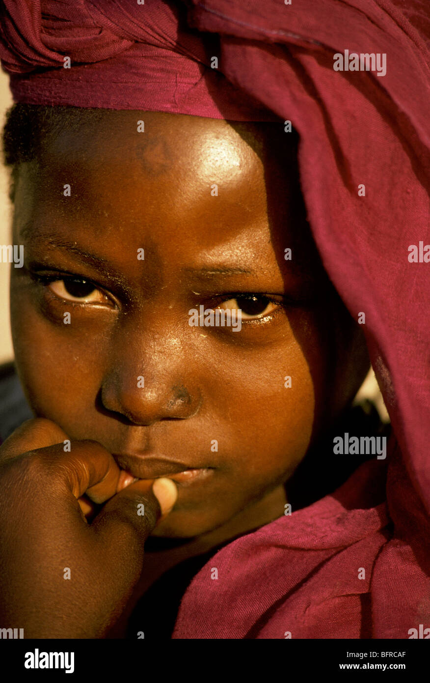 Portrait of a young African child wearing a maroon head scarf Stock ...