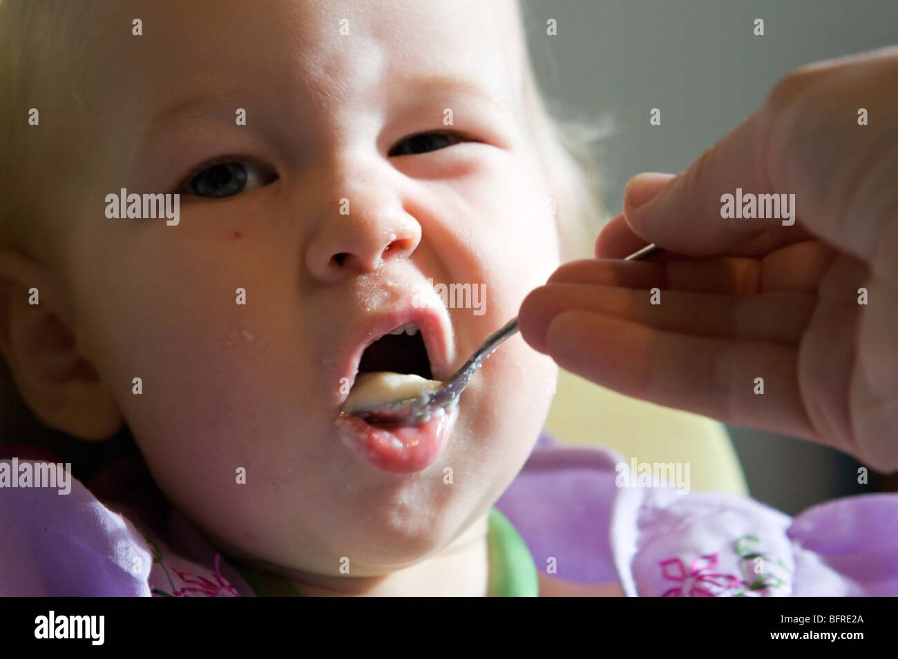 amusing baby with spoon of pap in a mouth Stock Photo - Alamy
