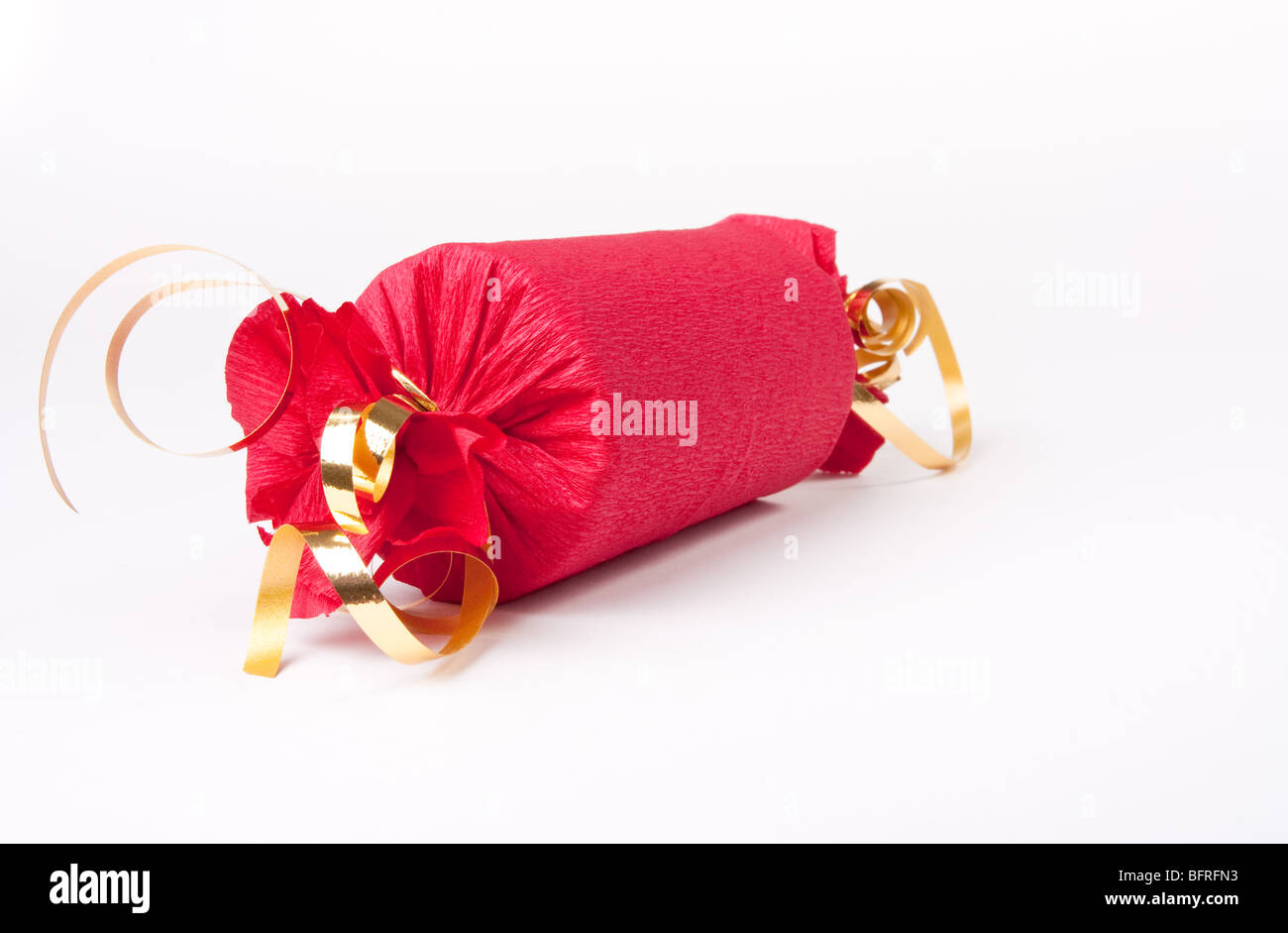 Homemade christmas cracker made from red crepe paper and gold ribbon ...
