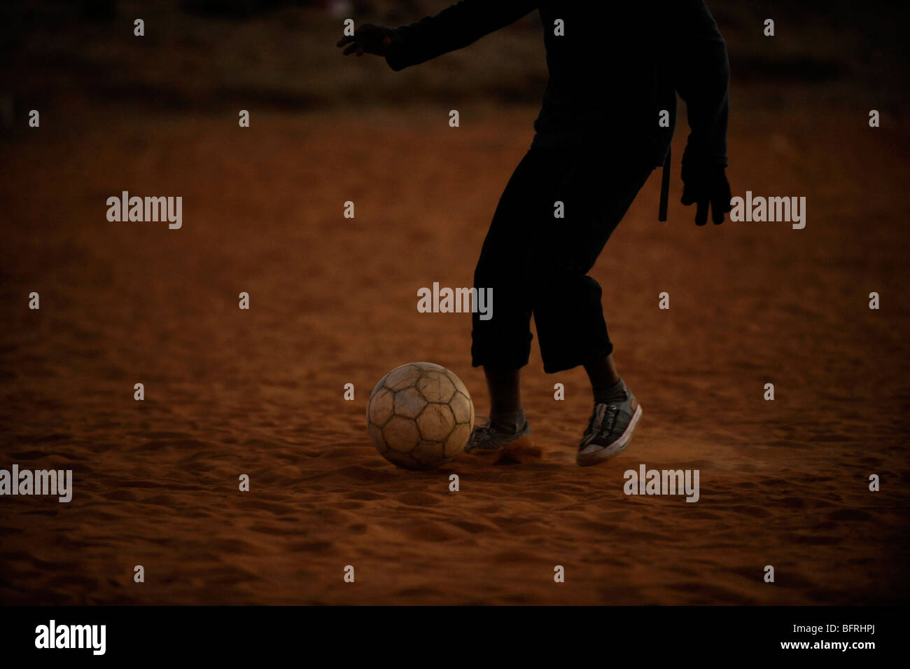 South African boy playing football on a sandy pitch Stock Photo - Alamy