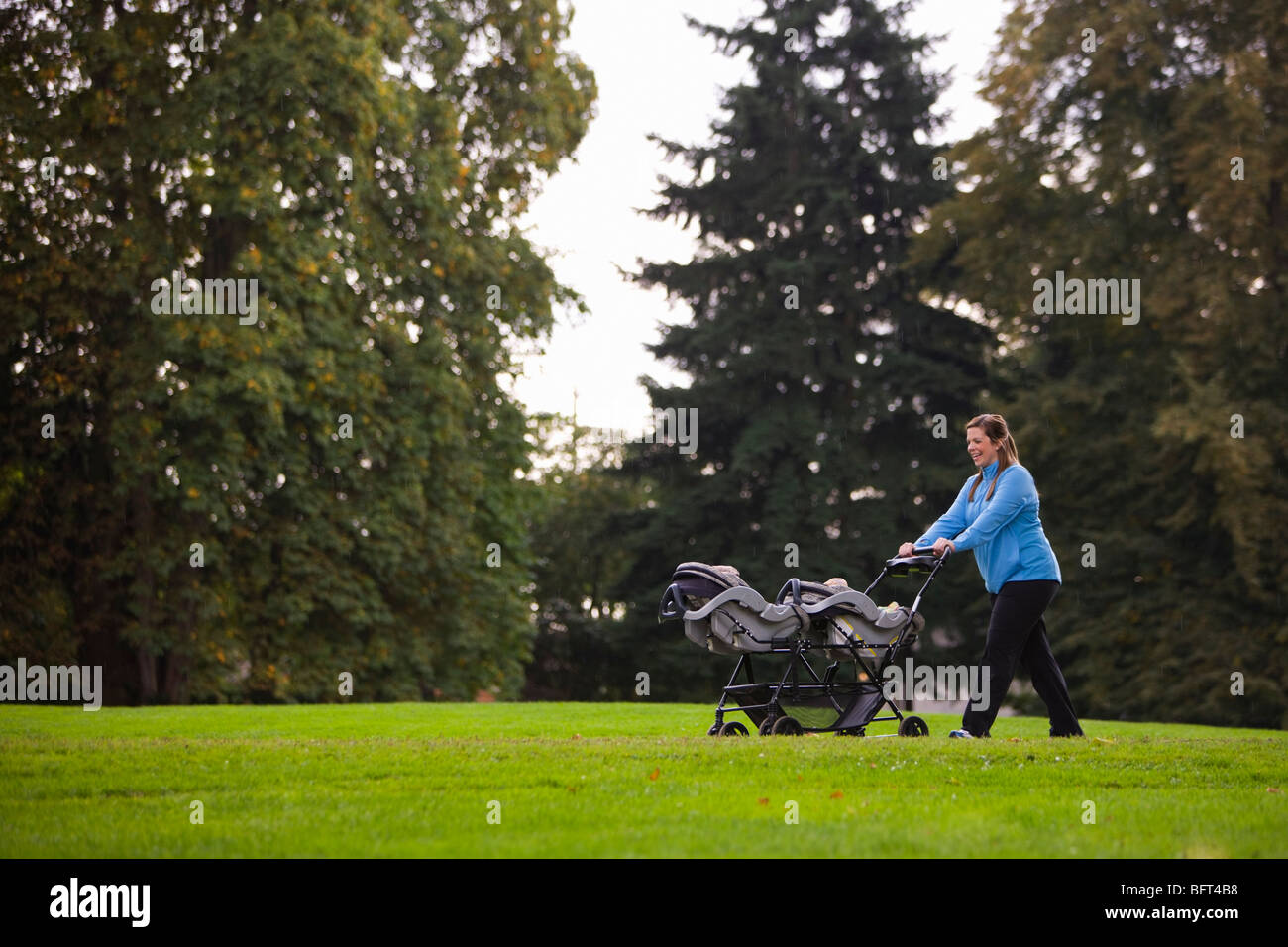 Woman Pushing Stroller in Park Stock Photo - Alamy