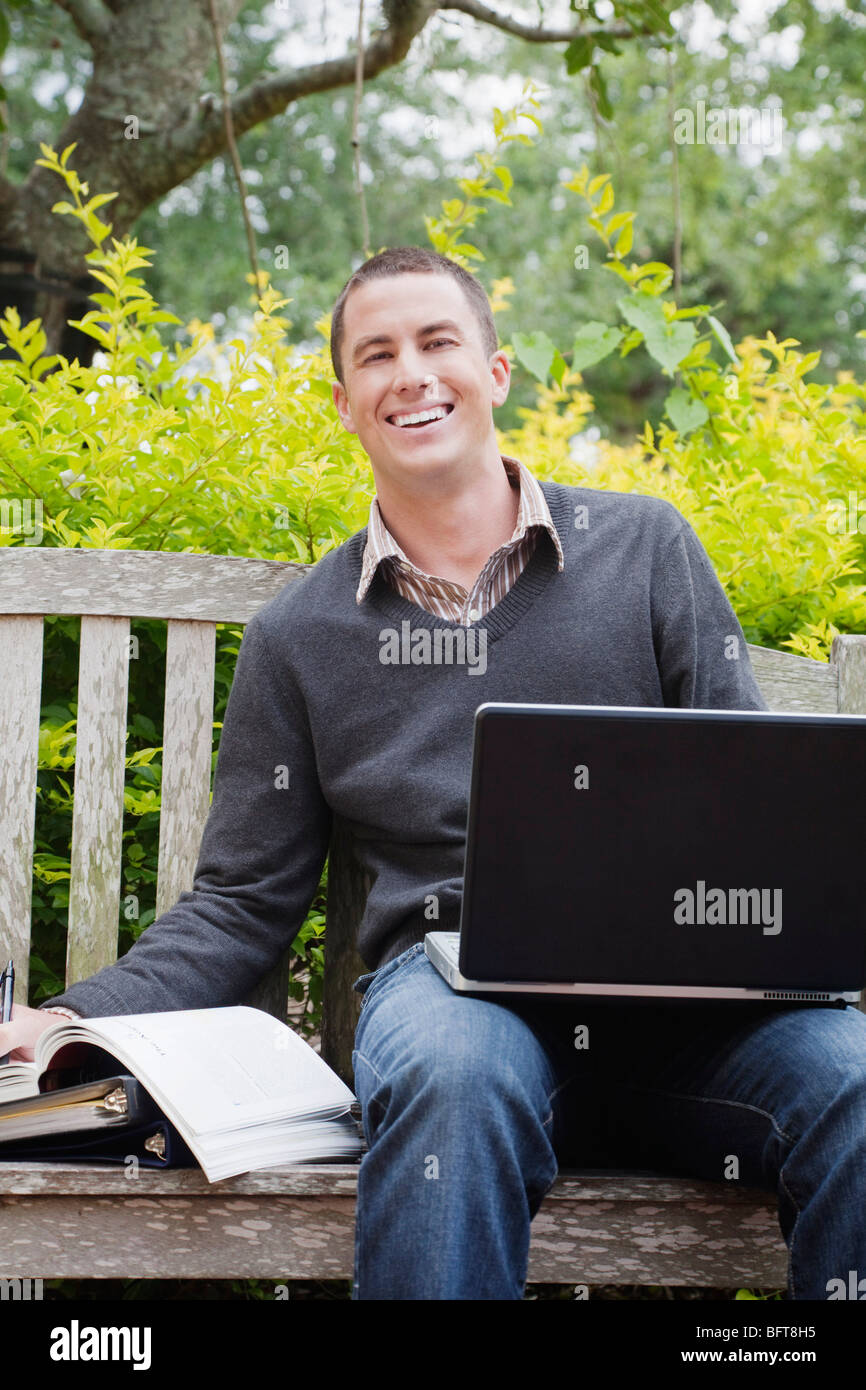 University Student Sitting on a Bench Using a Laptop Computer Stock ...