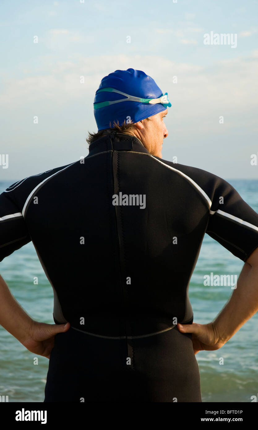 A back view of a muscular swimmer or triathlete wearing a wetsuit and ...