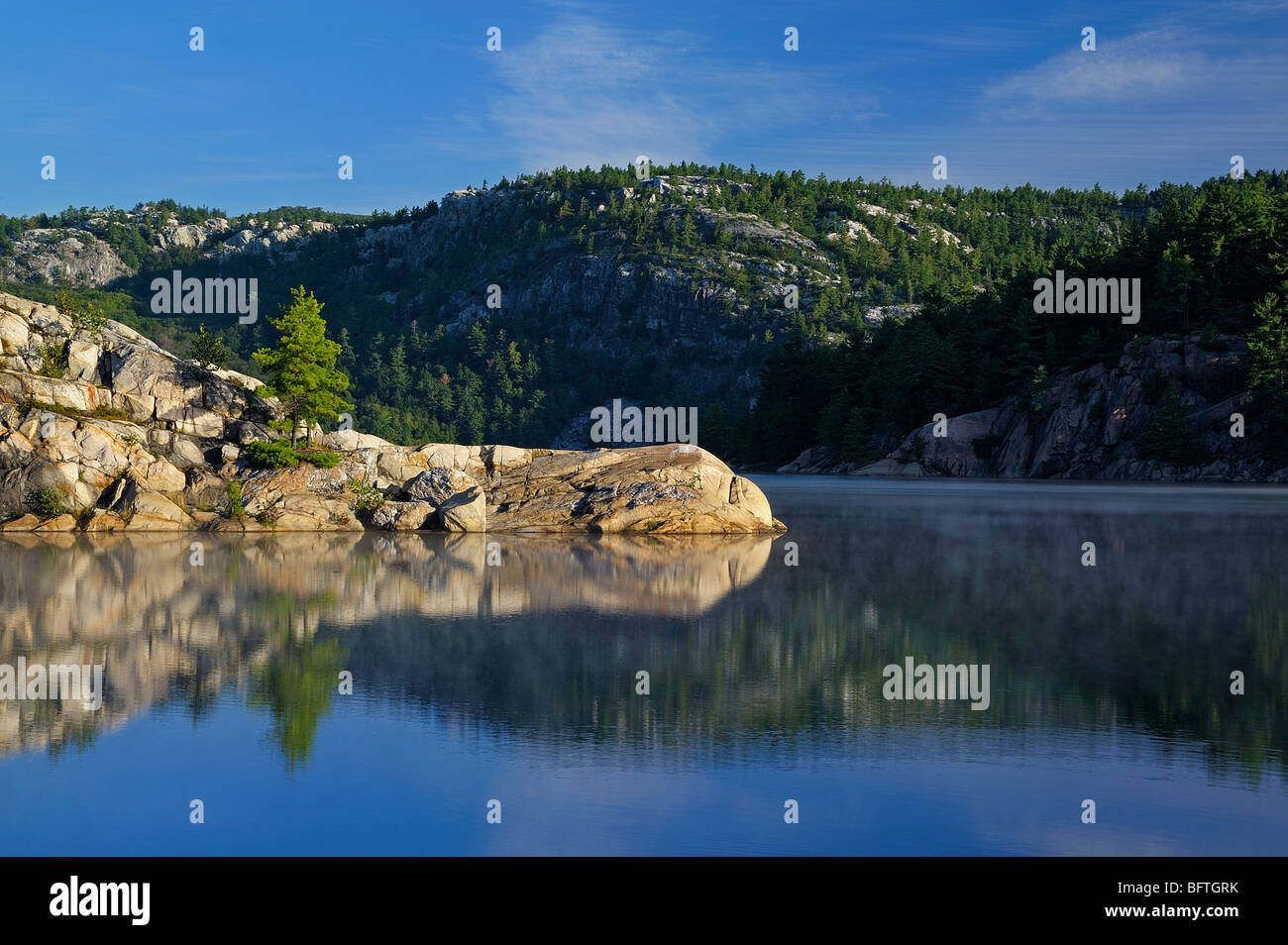 Cliffs and rocky points reflected in George Lake, Killarney Provincial ...