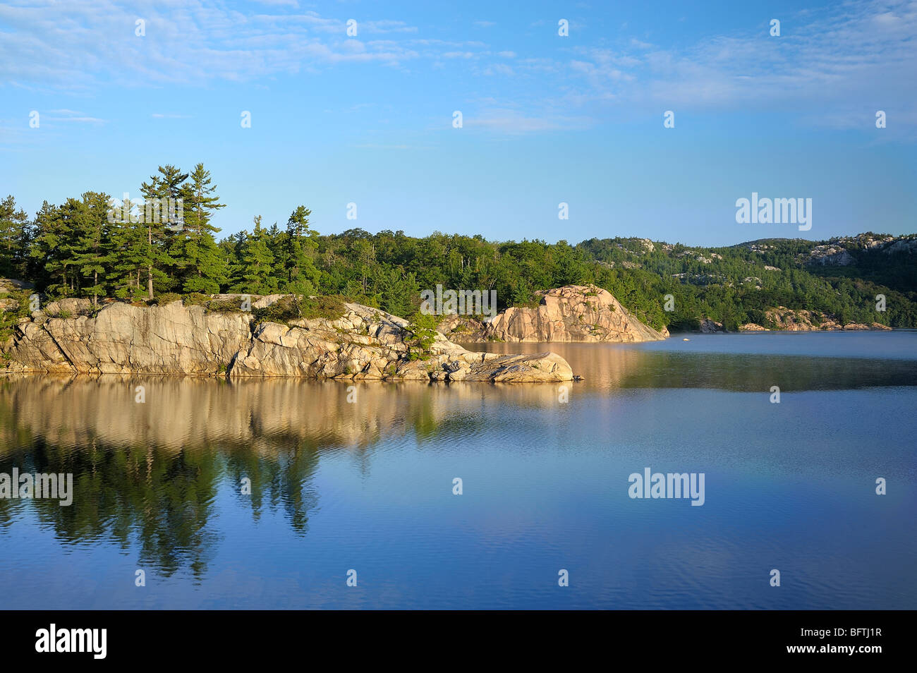 Cliffs and rocky points reflected in George Lake, Killarney Provincial ...