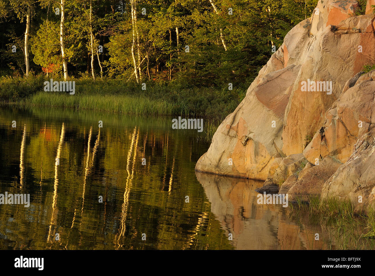 Granite cliff reflected in George Lake, Killarney Provincial Park ...