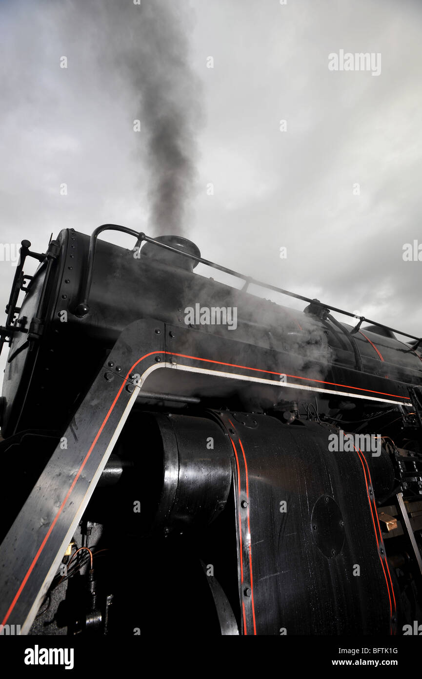 Steam locomotive warms up on a dark morning with black smoke from the ...