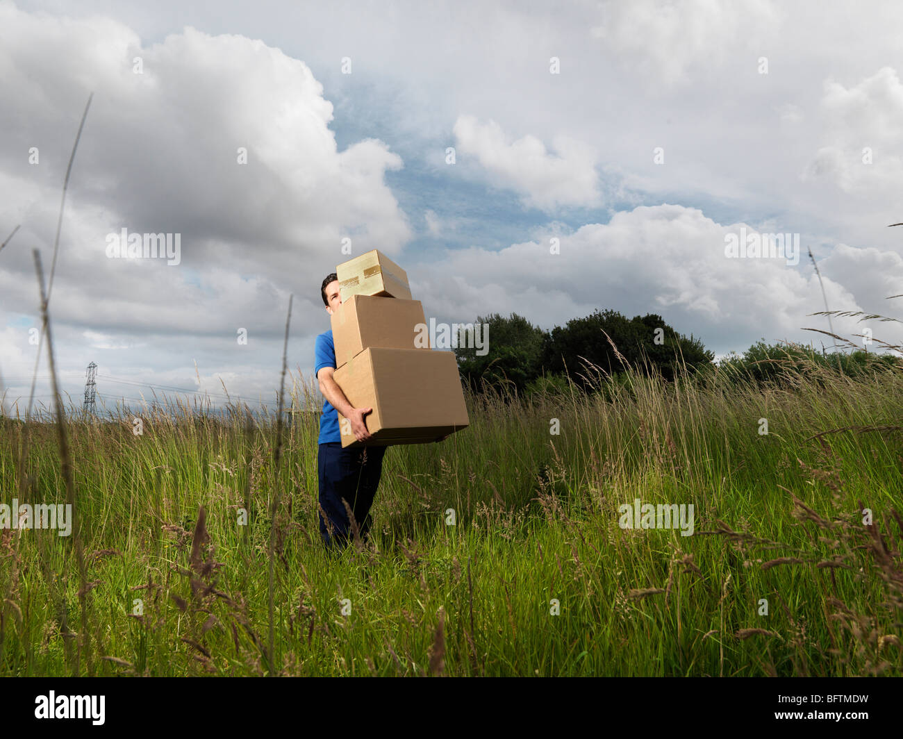 man carrying boxes through field Stock Photo - Alamy