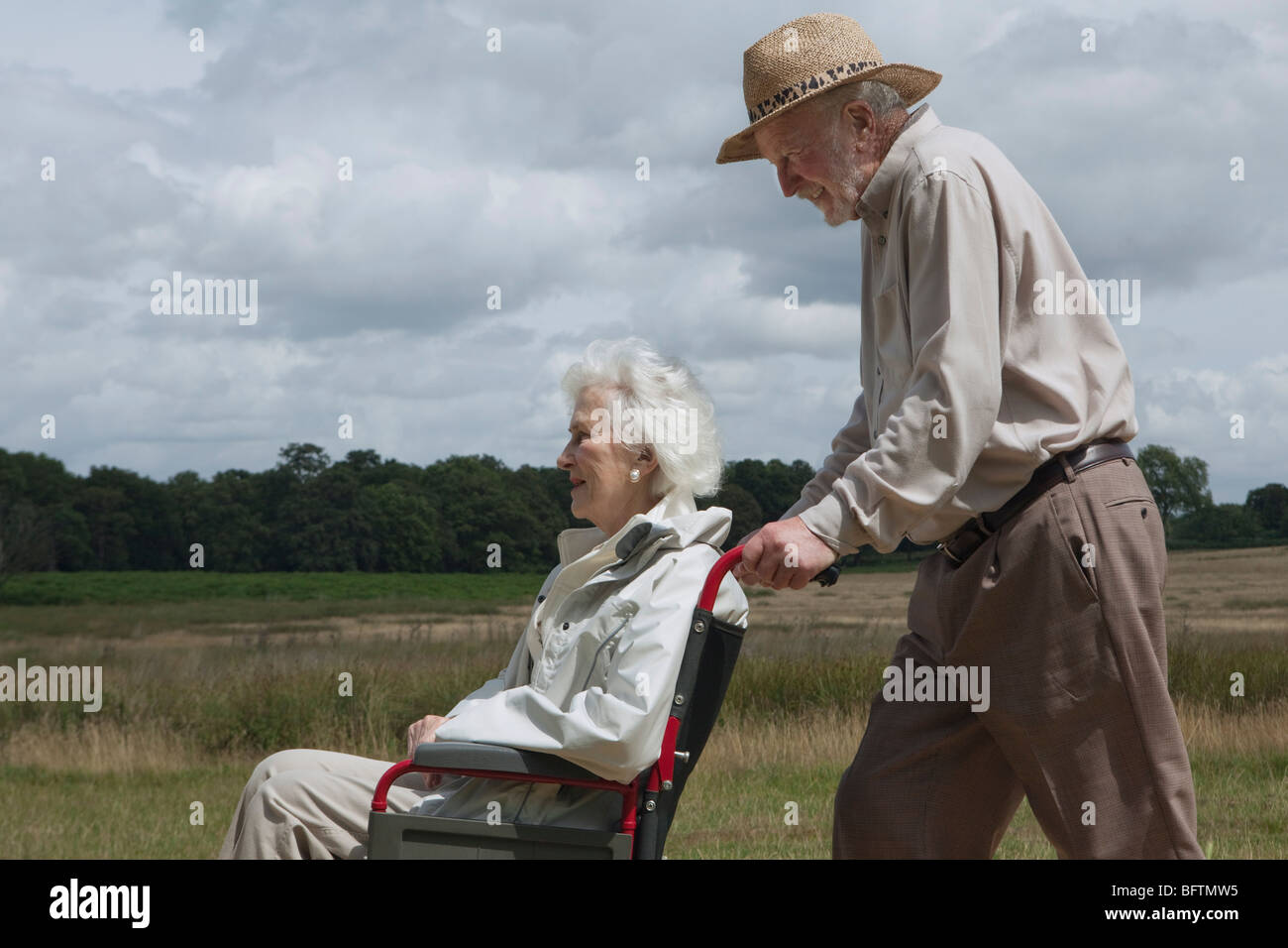 Elderly man pushing woman in wheelchair Stock Photo - Alamy