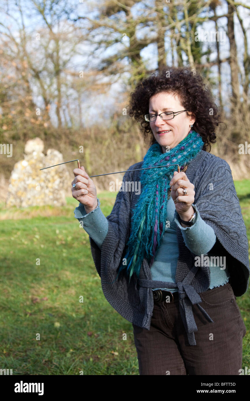 Woman Dowser smiling concentrating with L-shaped metal dowsing rods ...