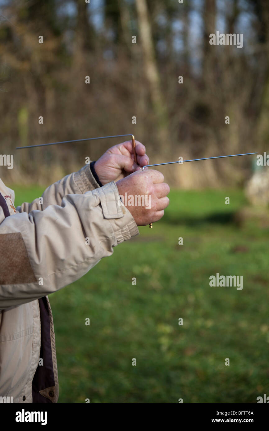 Dowser with L-shaped metal dowsing rods practising at Rollright Stones ...