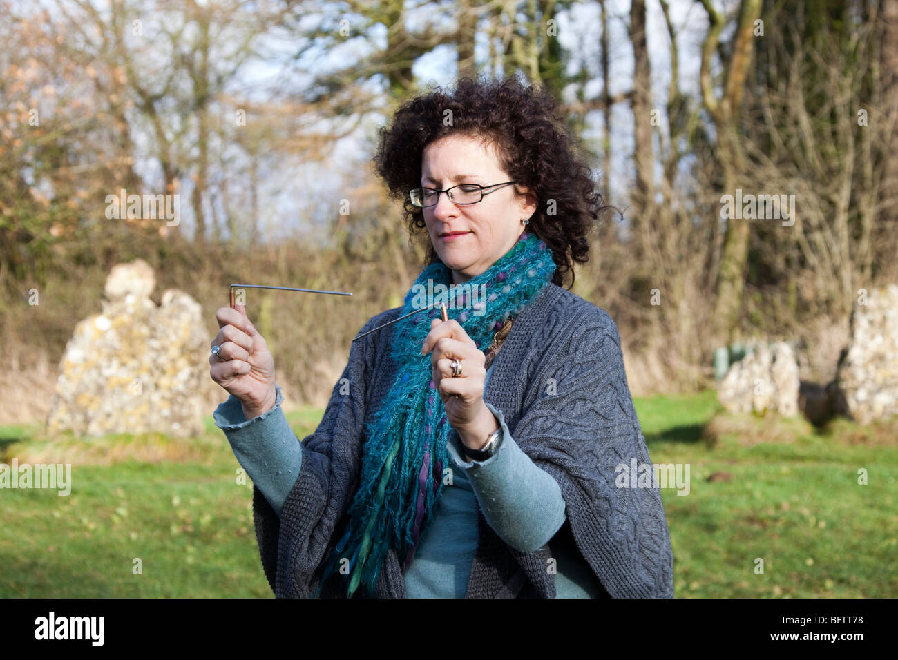 Woman Dowser with L-shaped metal dowsing rods practising at Rollright ...