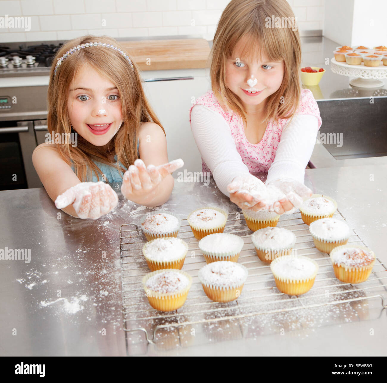 Two girls baking with icing sugar Stock Photo - Alamy