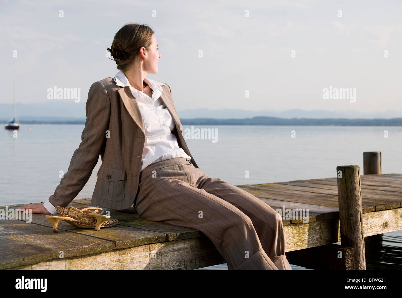 woman sitting on pier at lake Stock Photo - Alamy