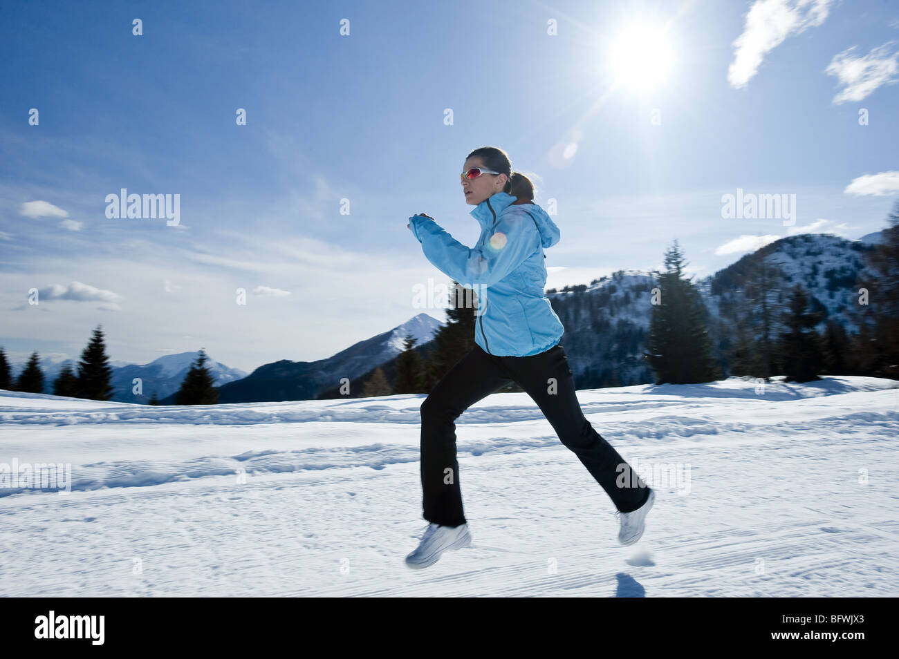 Young woman running in snow Stock Photo - Alamy