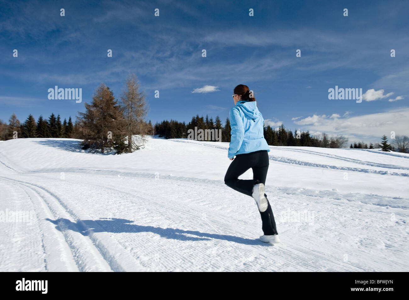 Young woman running in snow Stock Photo - Alamy