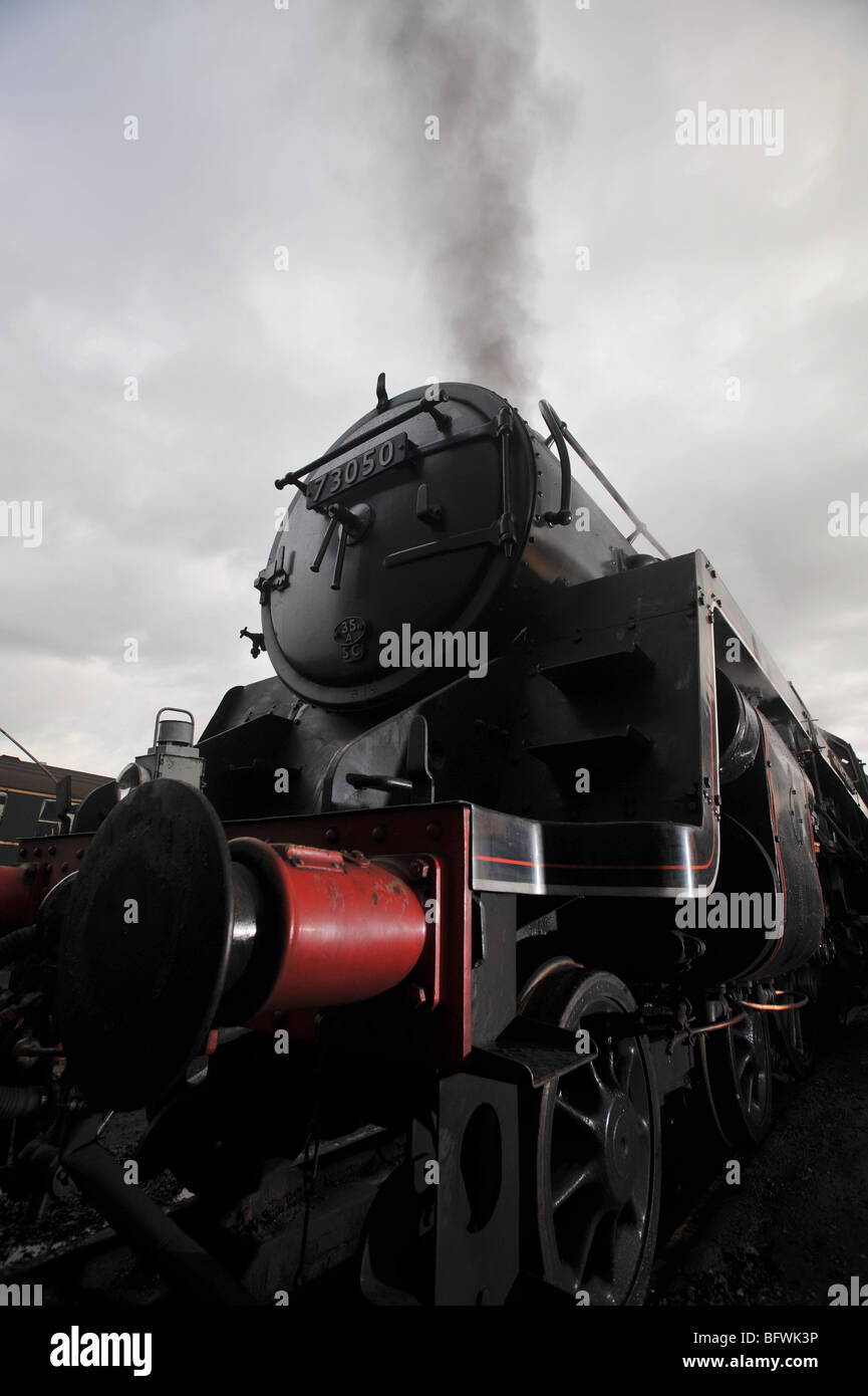 Steam locomotive warms up on a dark morning with black smoke from the ...