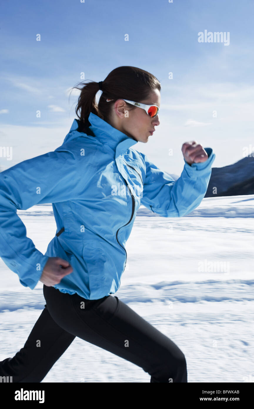 Young woman running in snow Stock Photo - Alamy