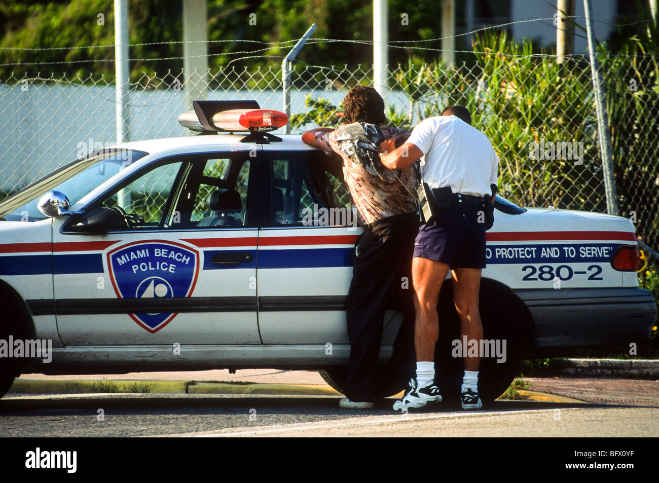 A Miami Beach police officer searches a suspect in Miami, Florida Stock ...