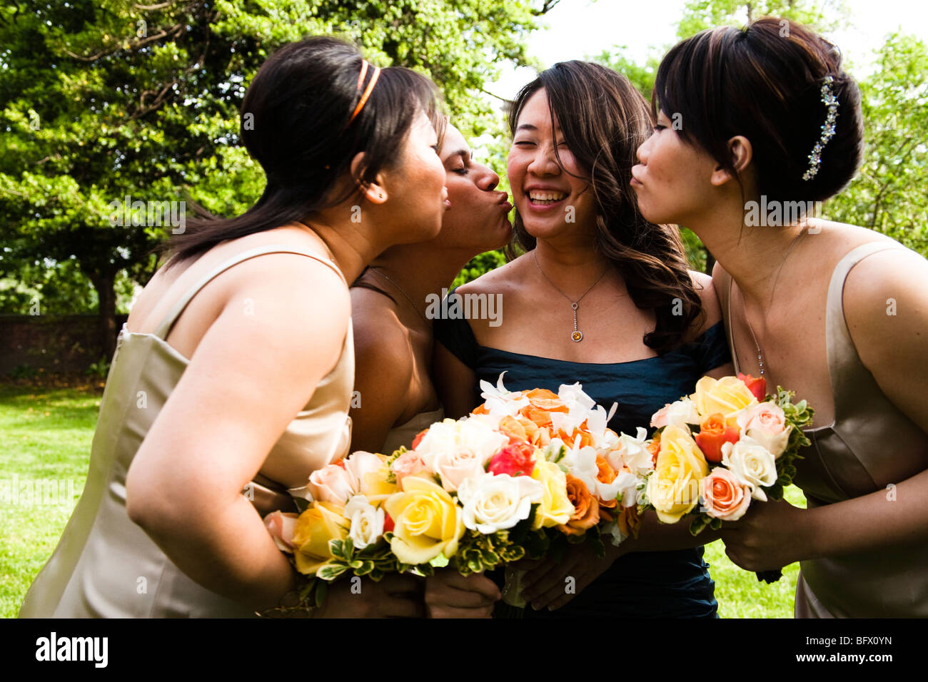 A bride getting kissed by her bridesmaids Stock Photo - Alamy