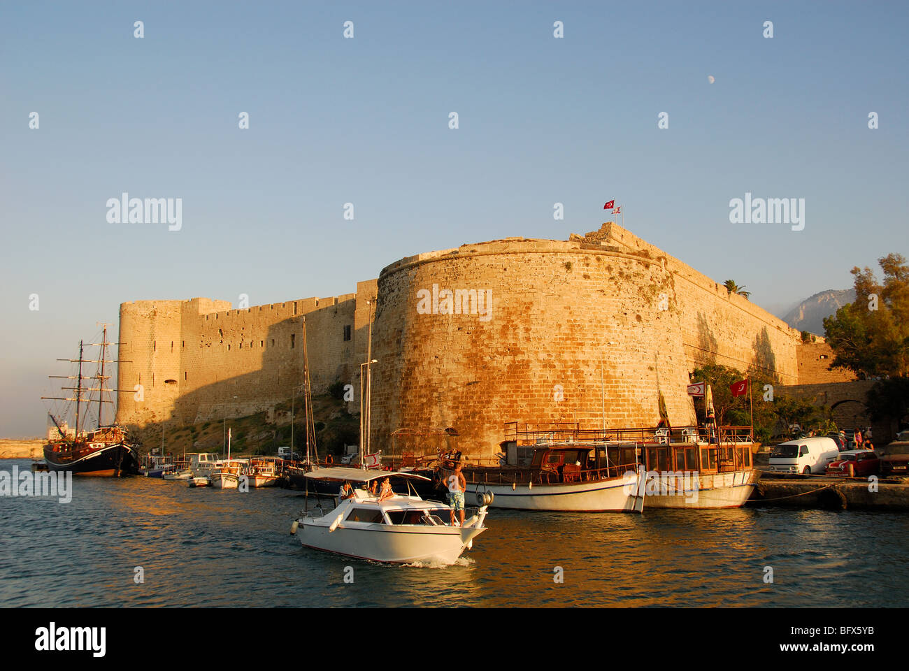 NORTH CYPRUS. A small boat sailing past Kyrenia castle on its way into ...
