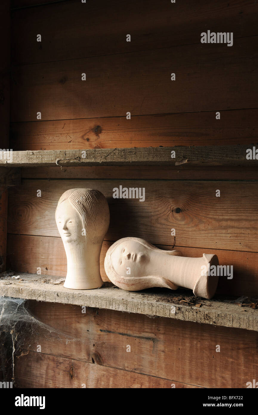 Two pot heads of women side by side on dusty shelf. One lies on its ...