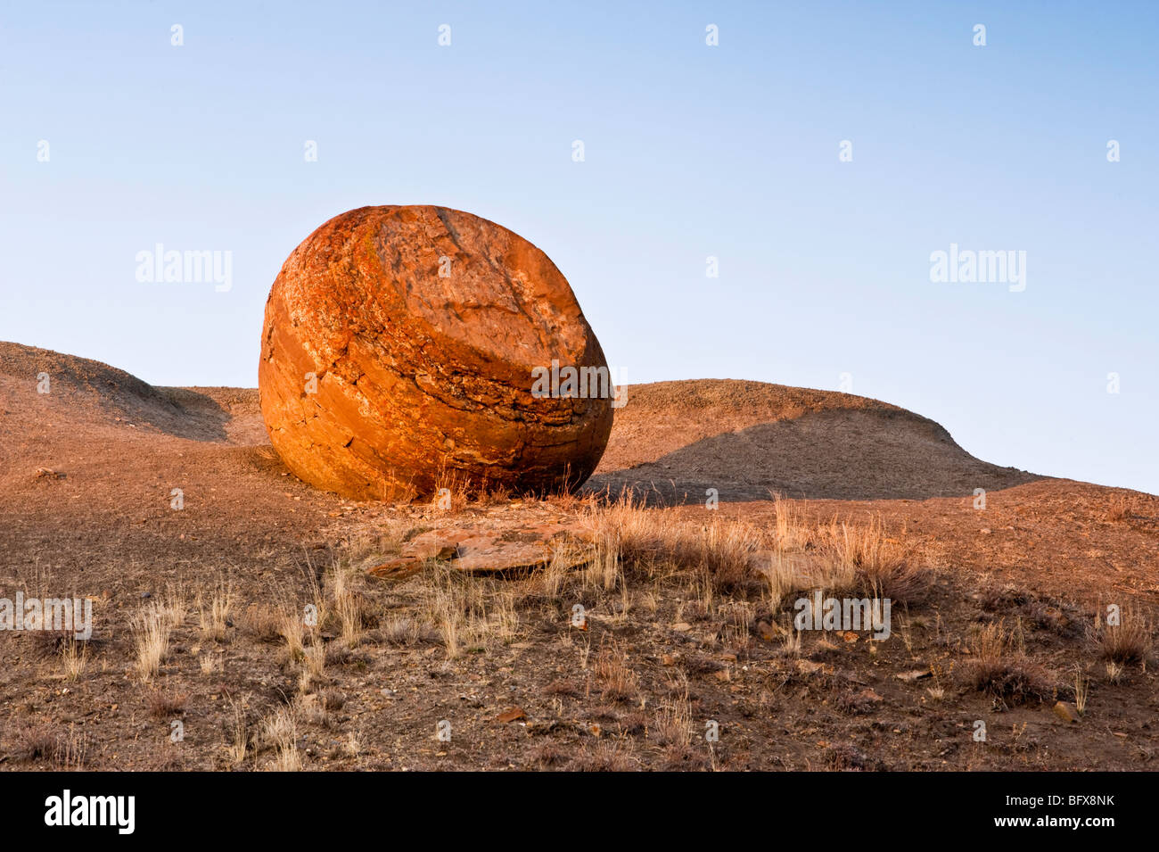 Eroded sandstone boulders exposed in semi-arid landscape at dawn, near ...