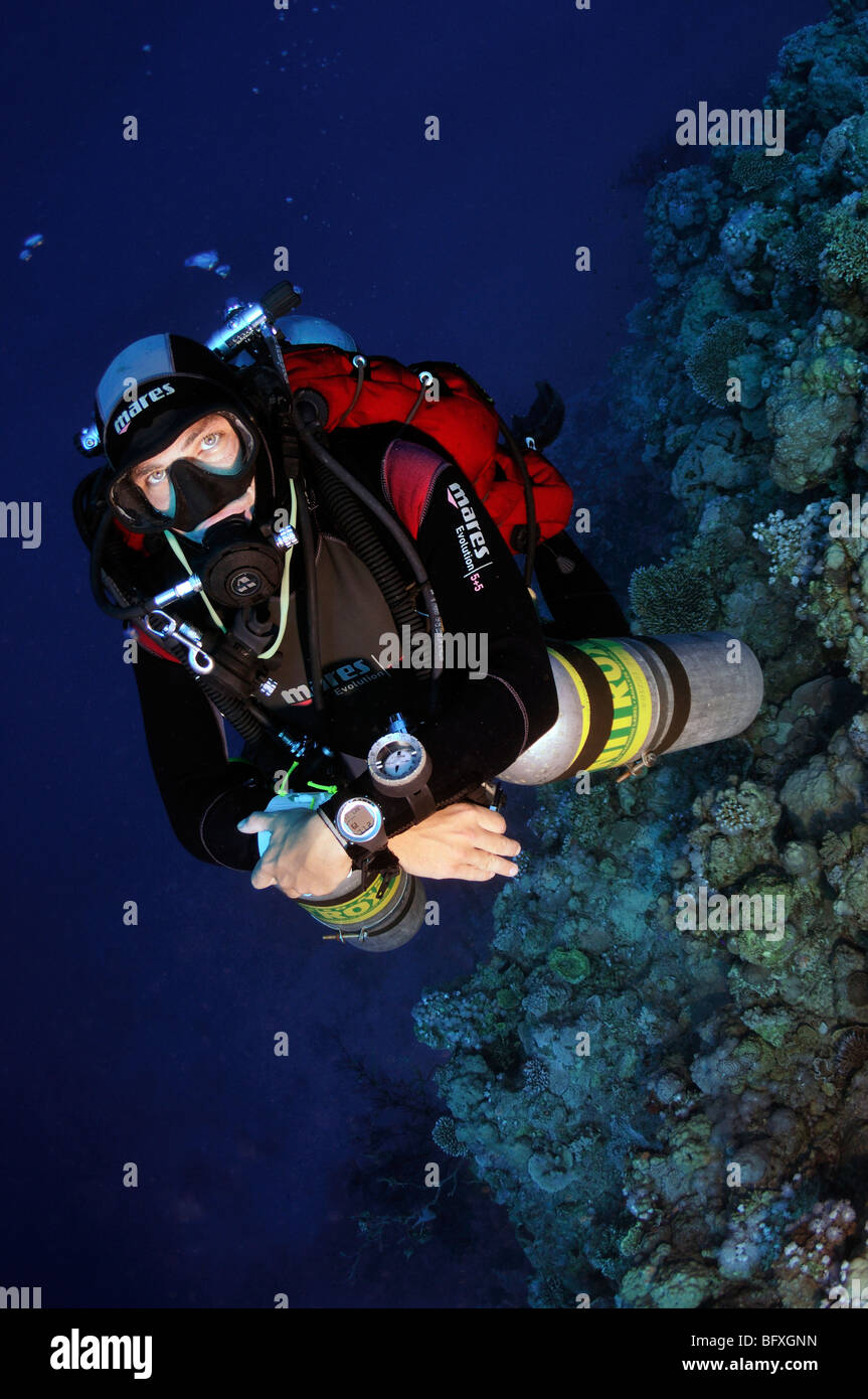 Technical scuba diver diving underwater with multiple cylinders on ...