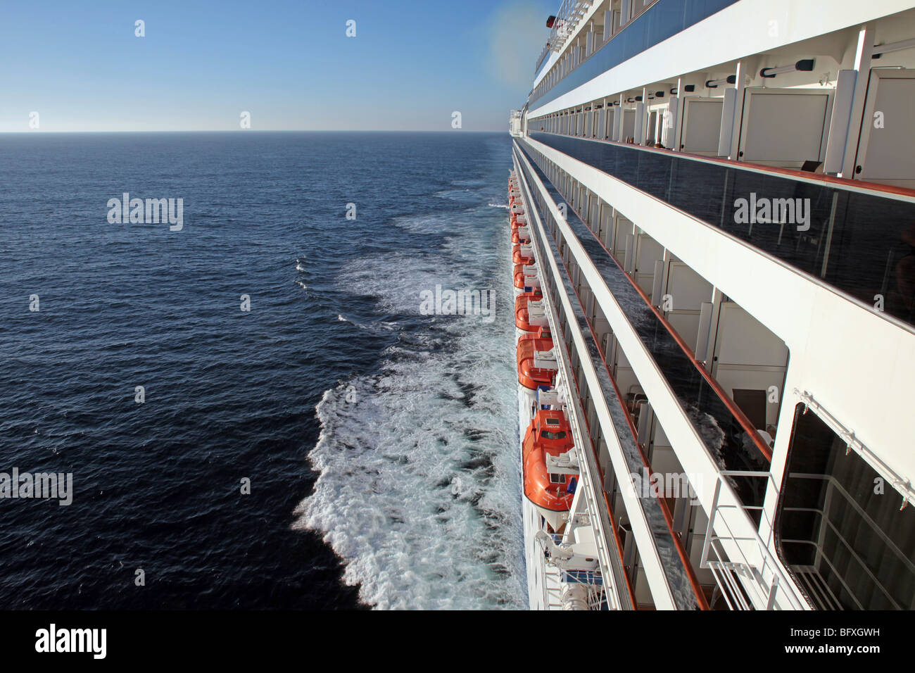 Cruise ship lifeboats, balconies and ocean wake looking down side of ...