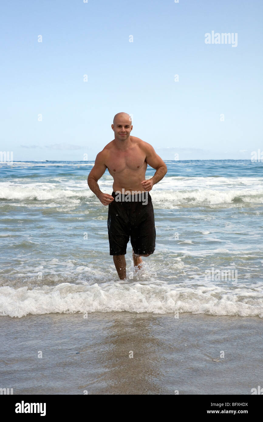 Muscle Man running out of ocean Stock Photo - Alamy