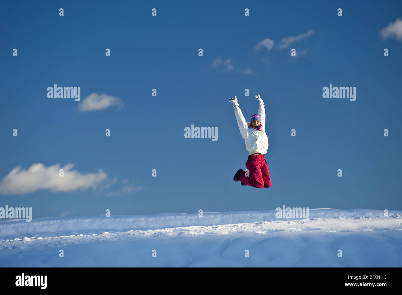 Young woman jumping in snow, arms outstretched Stock Photo - Alamy