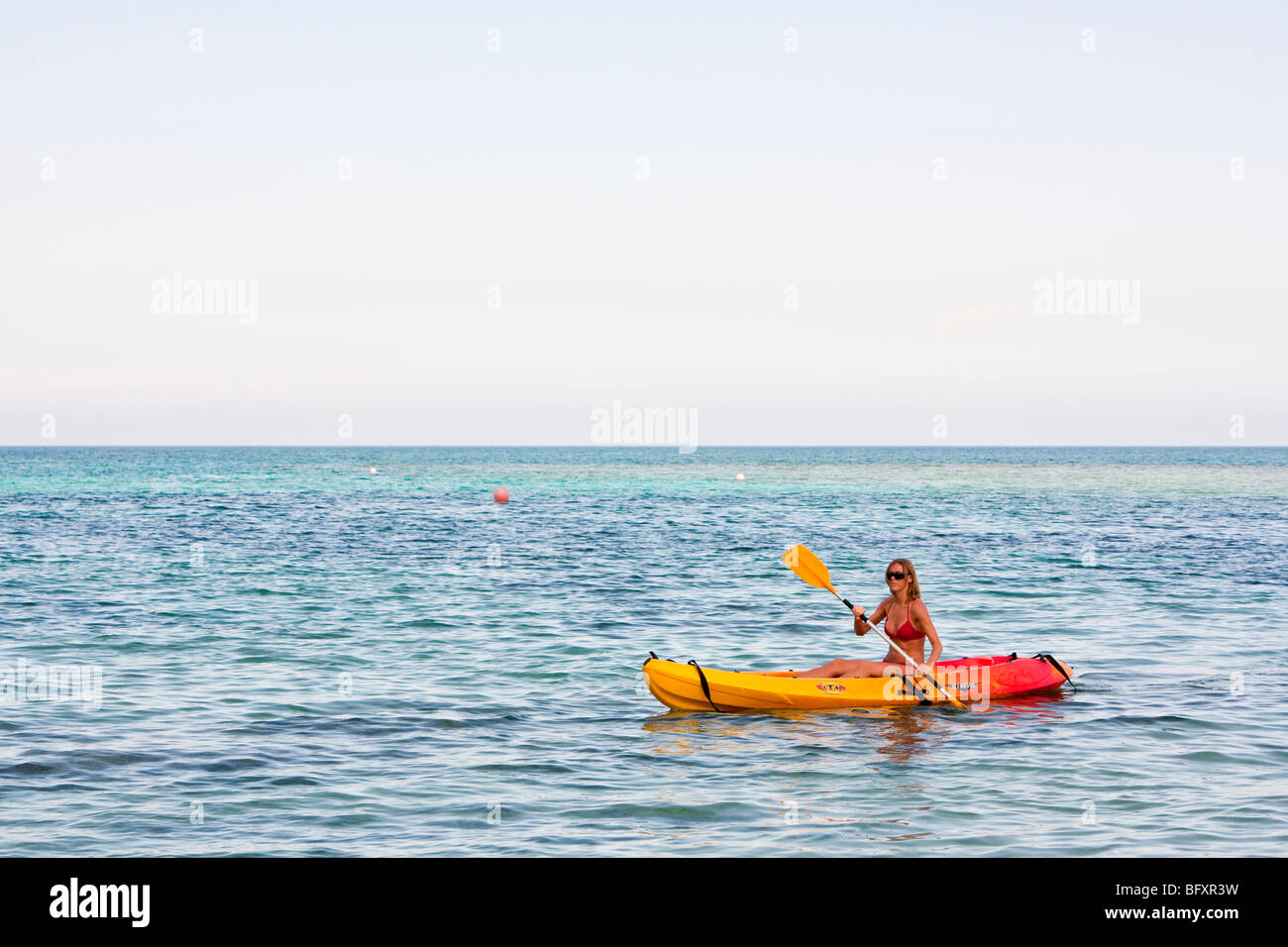 Young woman kayaking among coral reefs in the Atlantic Ocean, the ...