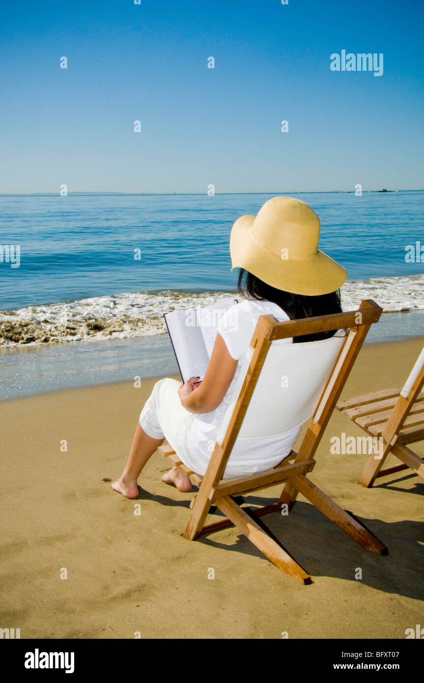 Woman reading book in chair on beach Stock Photo - Alamy