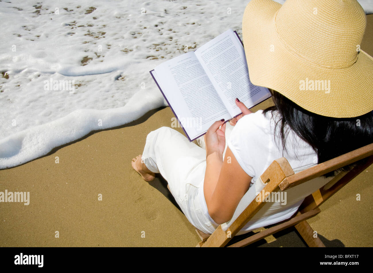 Woman reading book in chair on beach Stock Photo - Alamy