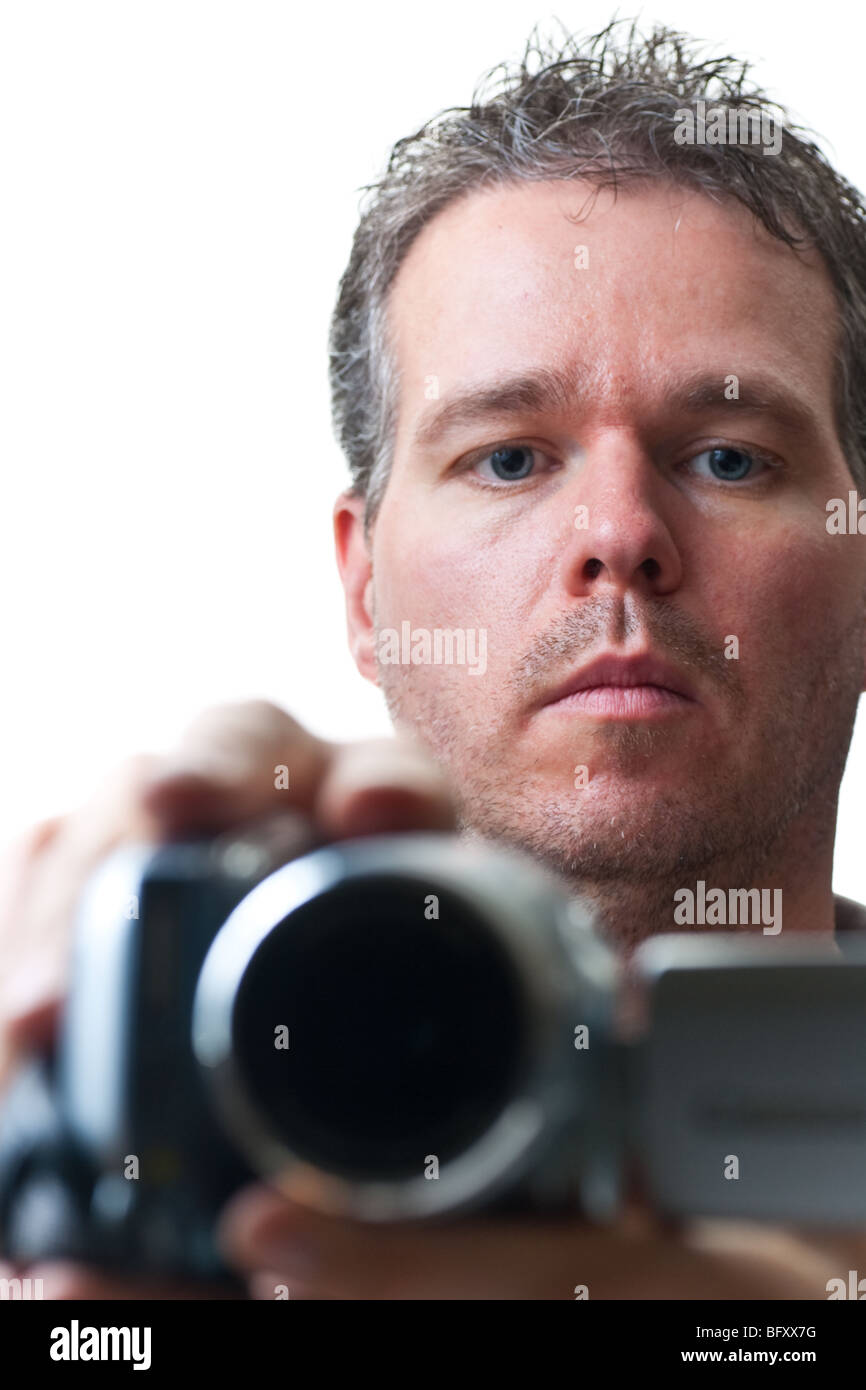 A man shooting with a video camera, focus on the man's face, isolated ...