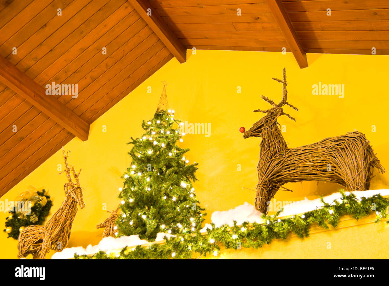 An indoor Christmas scene, with a lit Christmas tree, and two reindeer ...