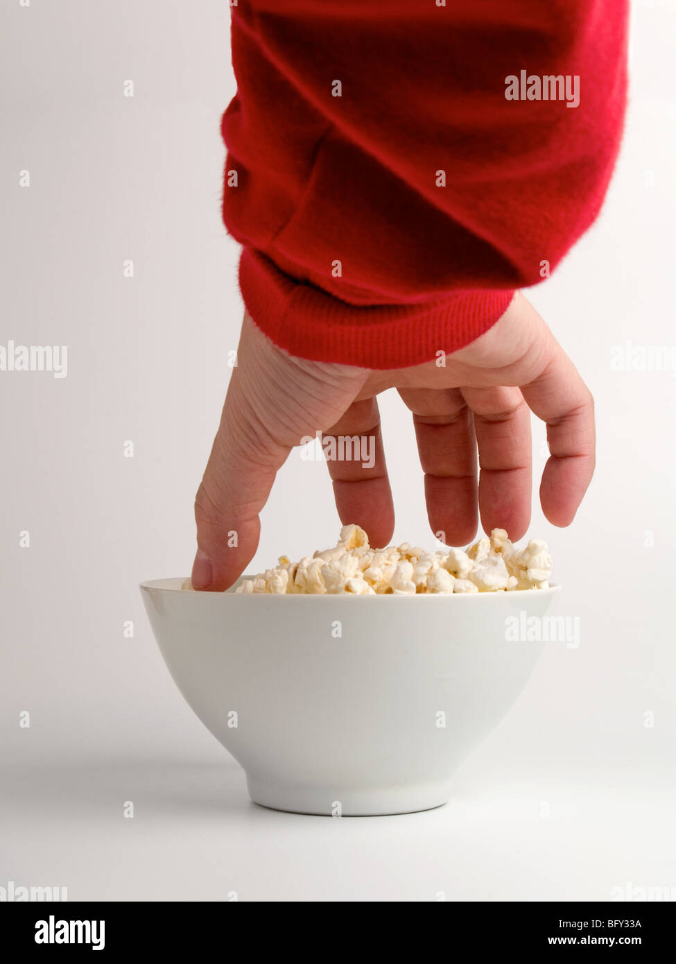 A hand trying to reach some popcorn from a bowl Stock Photo - Alamy