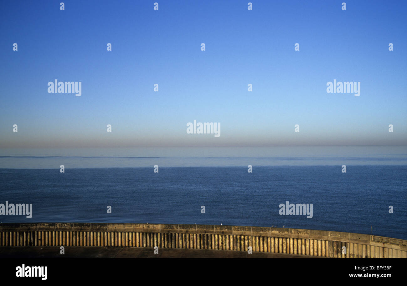 Looking out to sea across the retaining wall of a boating pool which is ...