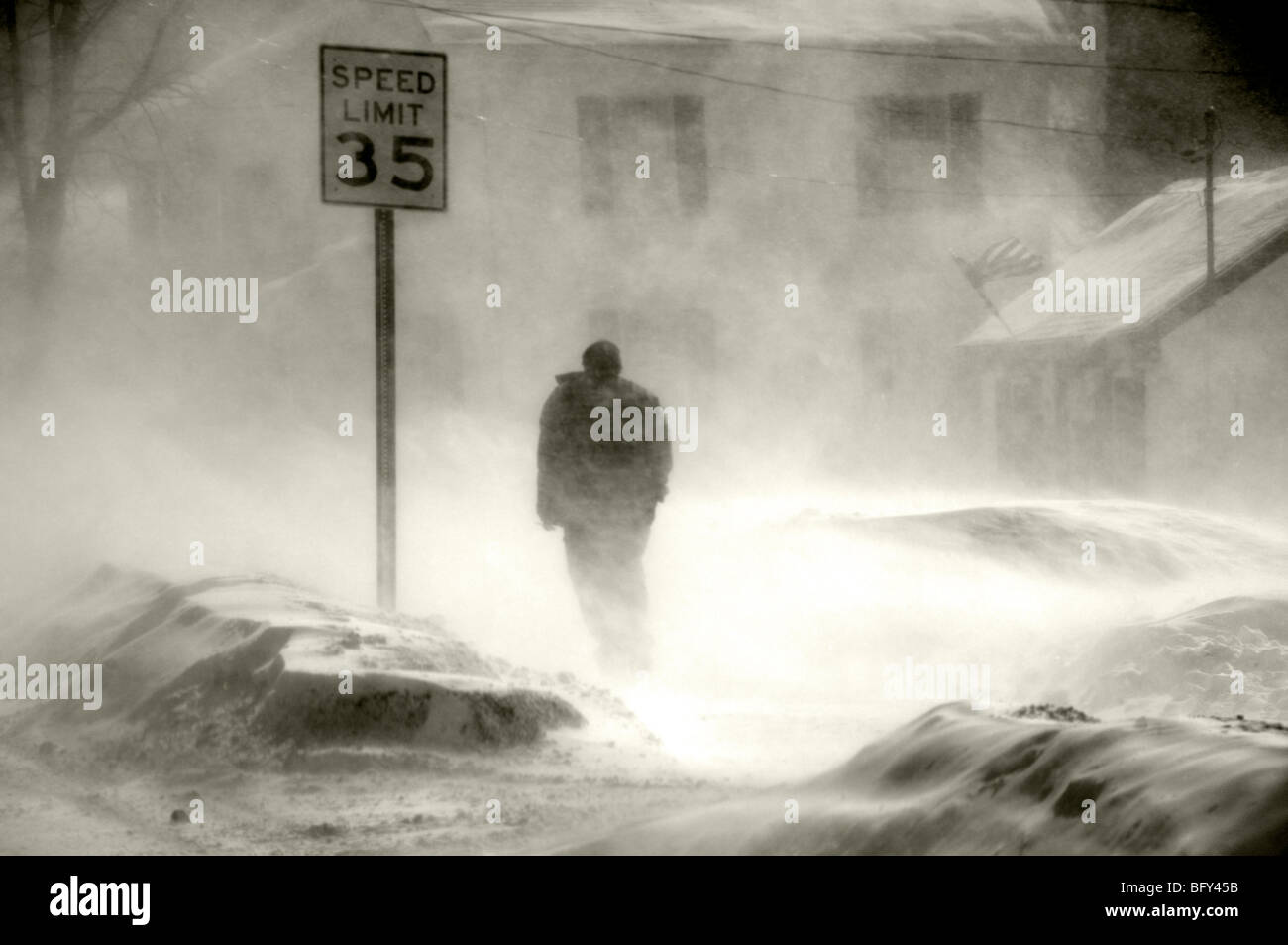 a man walking through a blizzard with speed limit sign Stock Photo - Alamy