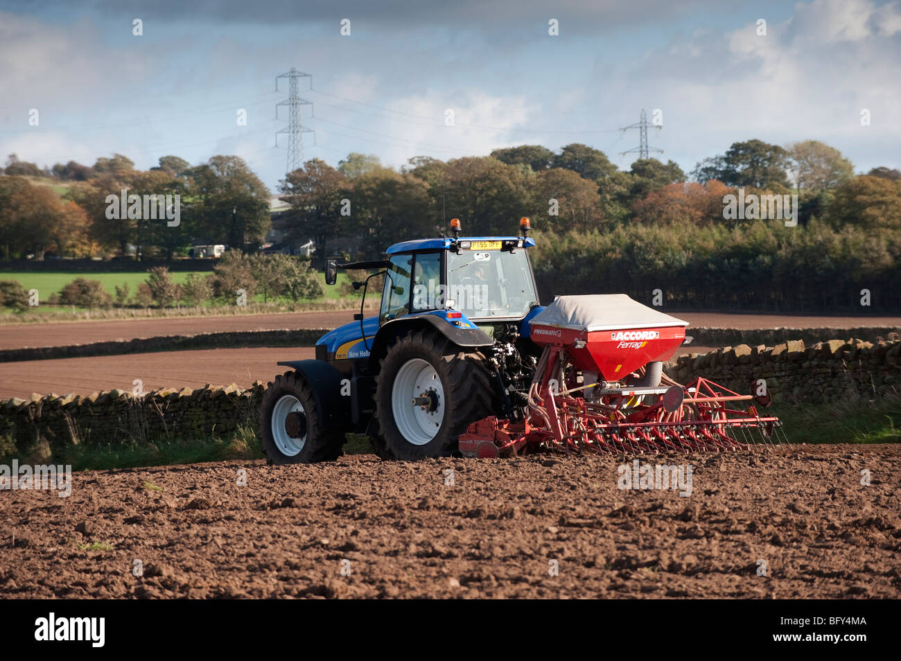 New Holland TM175 tractor and with seed drill planting winter barley ...