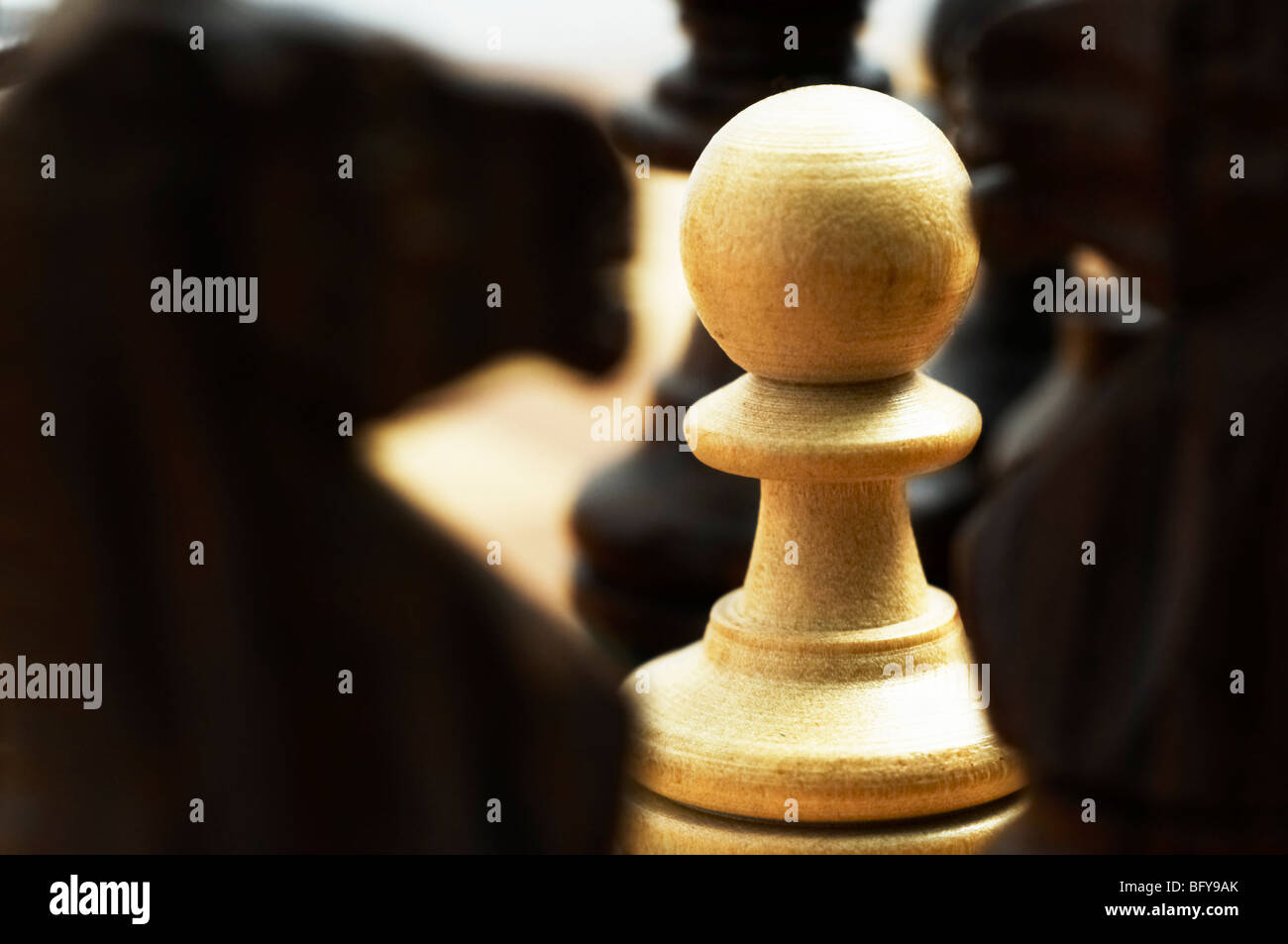 white pawn chessman surrounded by black pieces. concept - surrounded ...