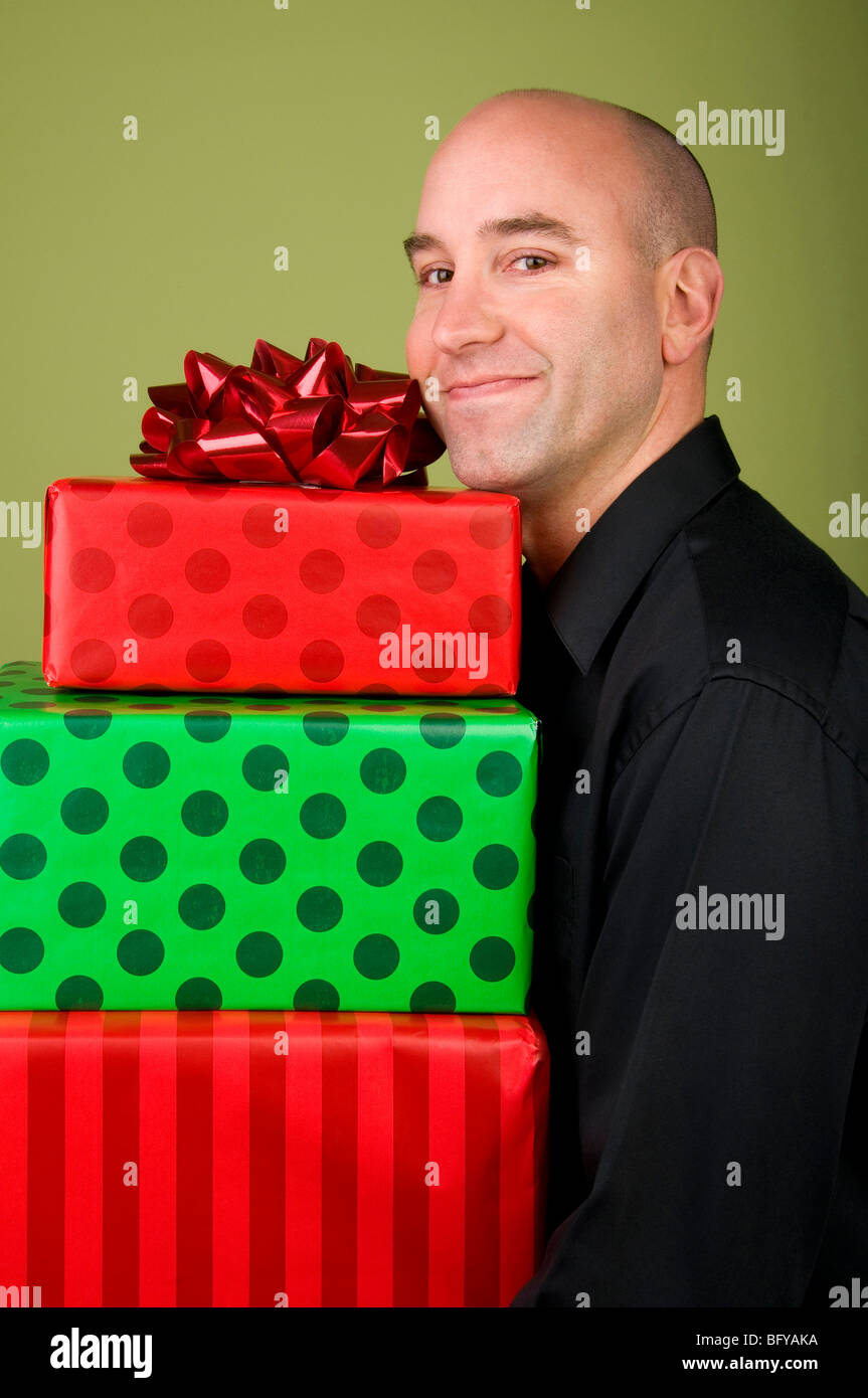 Man holding stack of Christmas gifts Stock Photo - Alamy