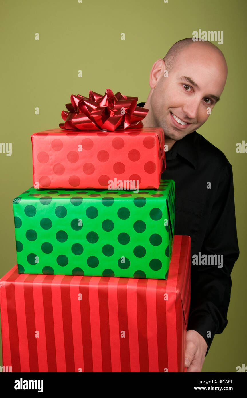 Man holding stack of Christmas gifts Stock Photo - Alamy
