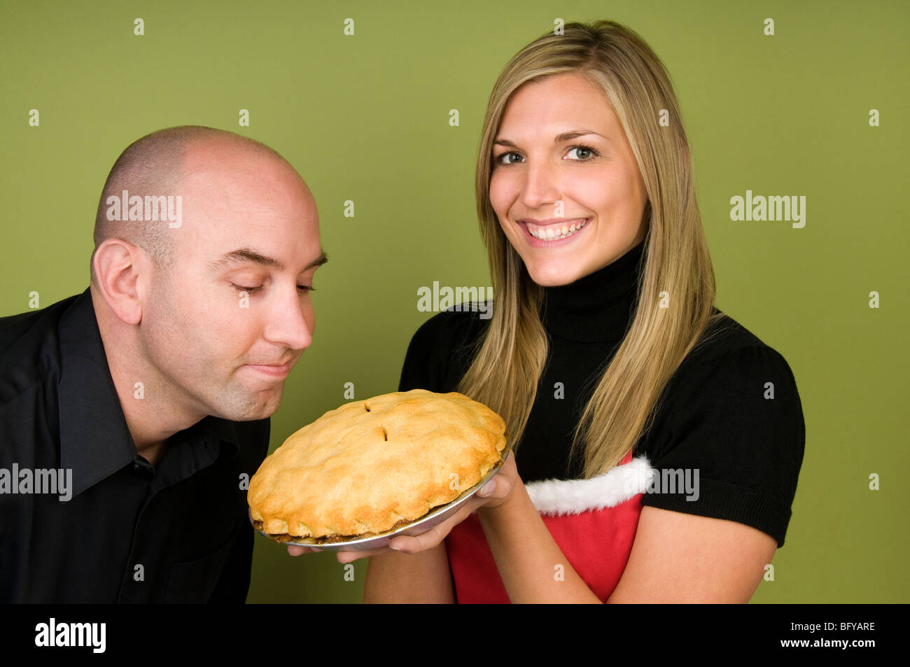 Man smelling pie held by woman Stock Photo - Alamy